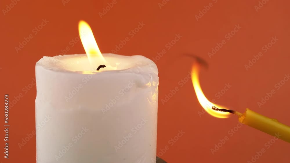 Blowing Out Flame Two Burning Church Candles on a Orange Background ...