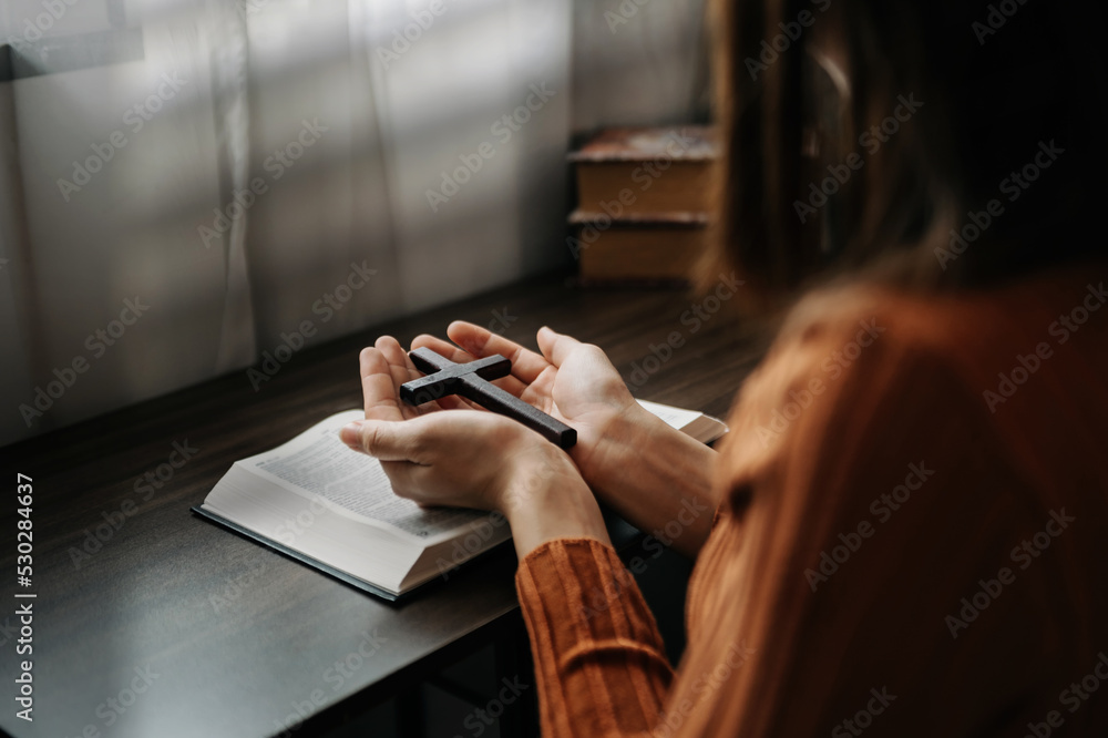 Woman sitting and studying the scriptures.The wooden cross in the hands ...