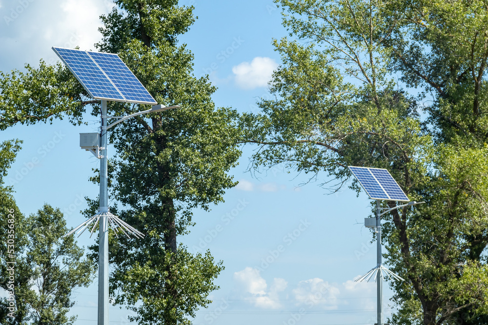 Lamp post with solar panel system on road with blue sky and trees ...