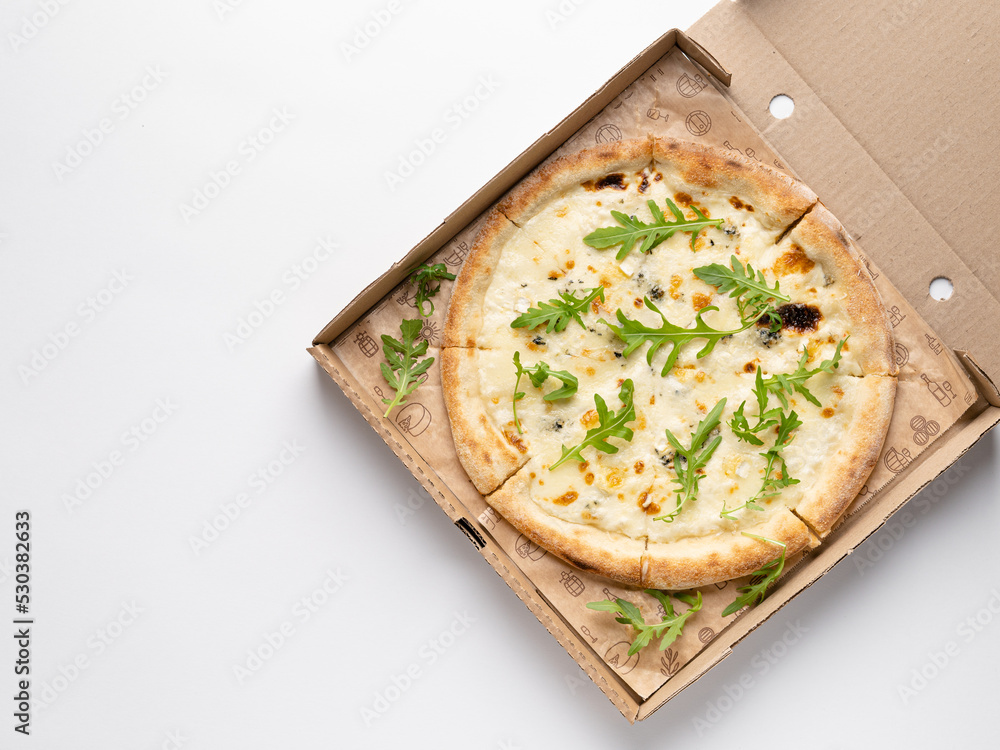 Pizza quattro formaggi (four cheese pizza) served with rocket salad leaves in cardboard box ...