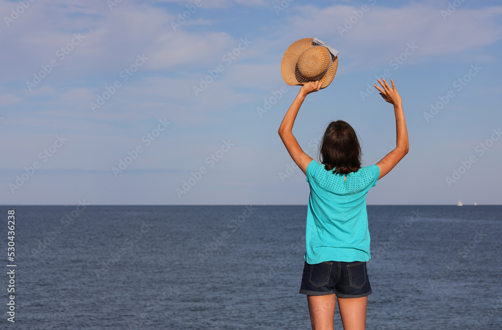 young girl with boater straw hat by the sea during summer vacation ...