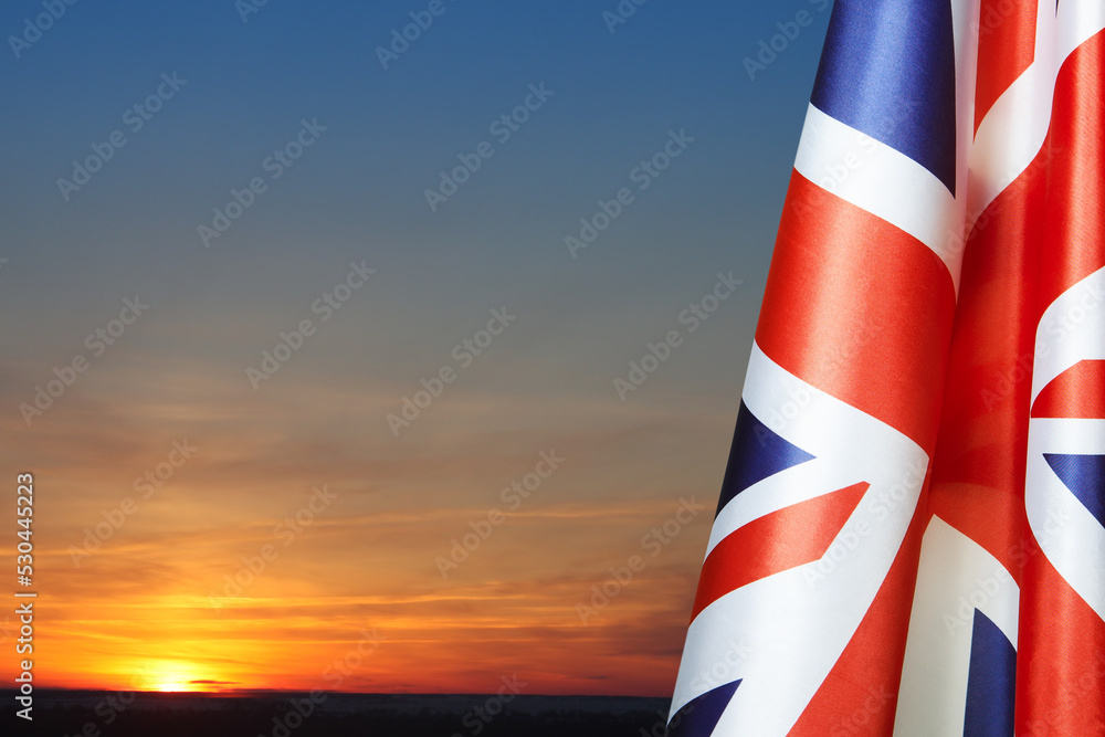 National flags of United Kingdom on a flagpole on sunset sky background ...