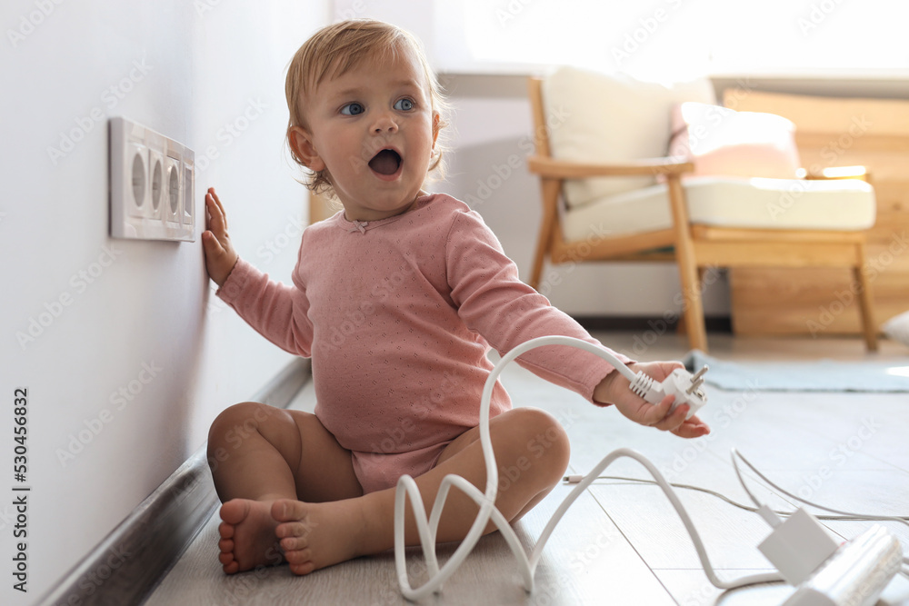 Foto de Cute baby playing with electrical socket and plug at home ...