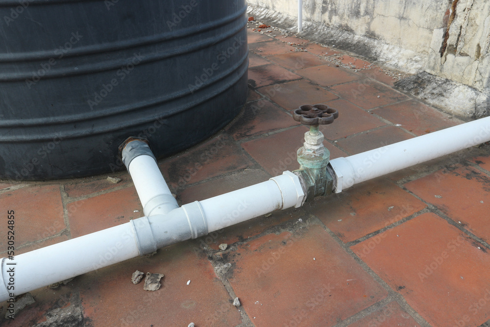A pipe with a valve departs from a black water tank on the roof of a ...
