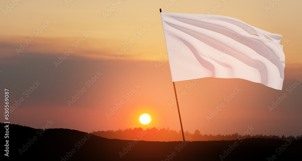 White flag waving in the wind on flagpole against the sunset sky with ...