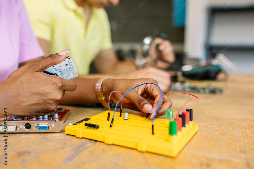 Close up female student hands creating electronic circuits and robotics ...