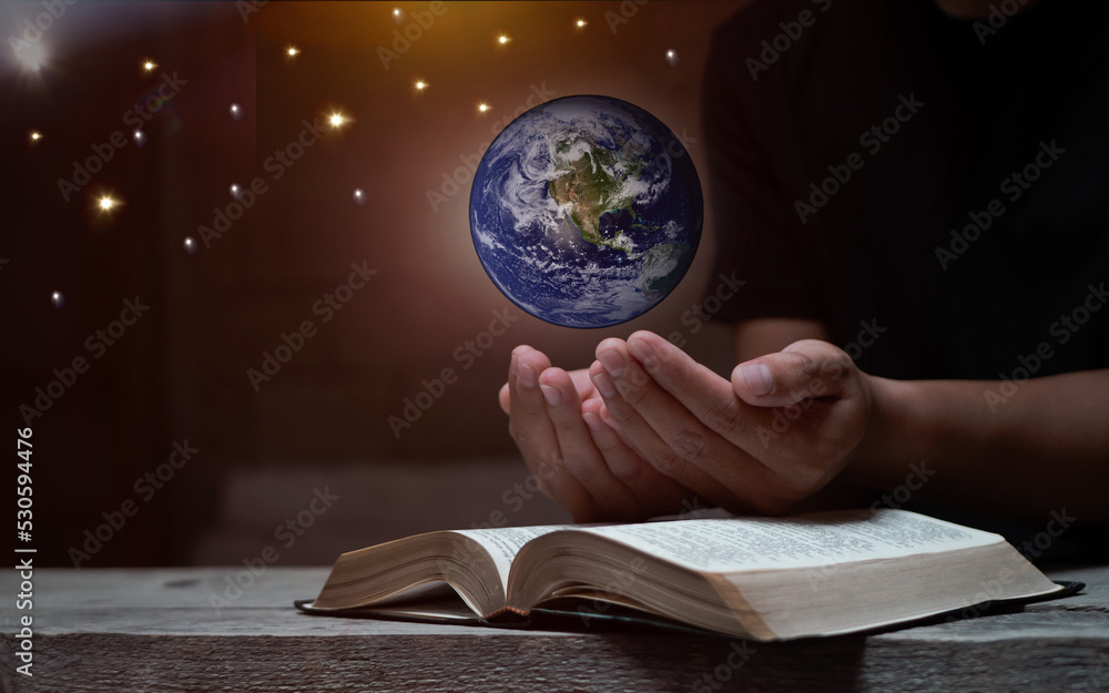 A man read the bible while lay hand and praying on blurred world globe ...