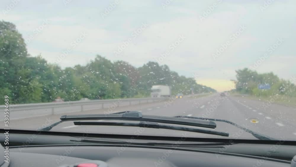Rain falling on car windshield view. Drive car on traffic jam street at ...