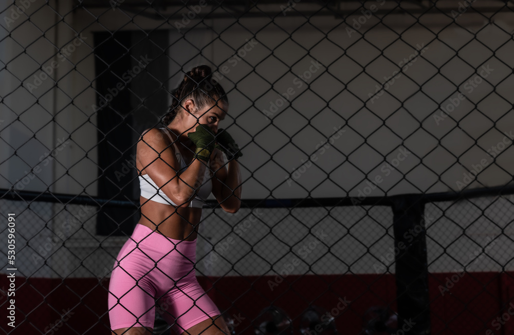 Foto de Young woman or girl mixed martial arts boxer fighter training in the octagon cage ...