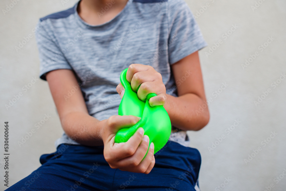 Teen boy playing with anti stress sensory ball squeeze toy. Giant ...