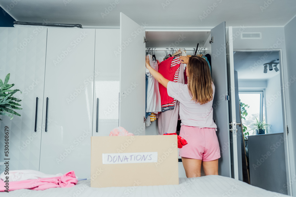 Woman selecting clothes from her wardrobe for donating to a Charity ...