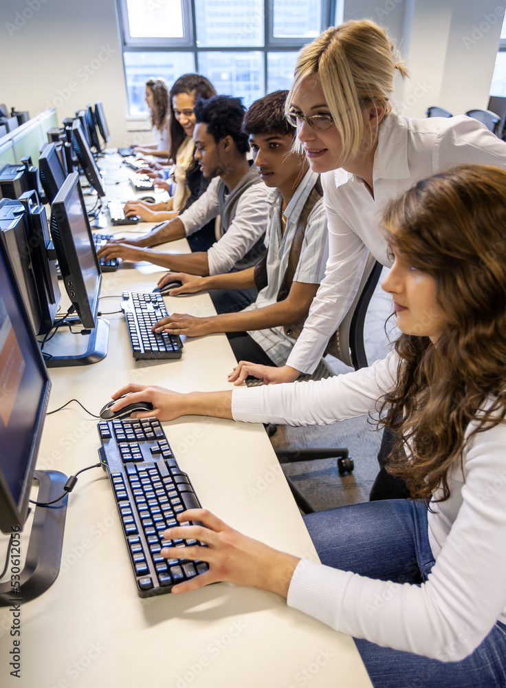 Teenage Students: Tech Class. A teacher helping senior school students ...