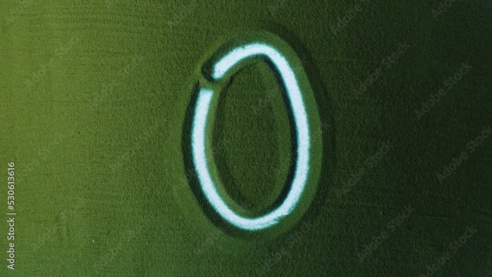 Hand drawing Number Zero 0 Symbol in the Green Sand. Male hand writes a ...