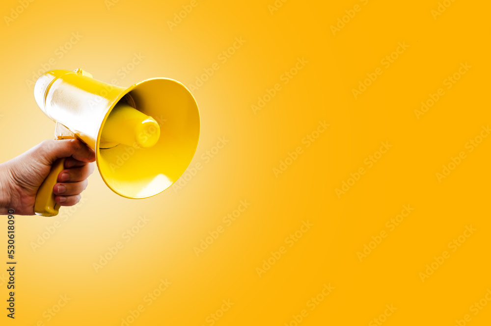On a bright yellow background, a yellow megaphone is in the hand of a ...