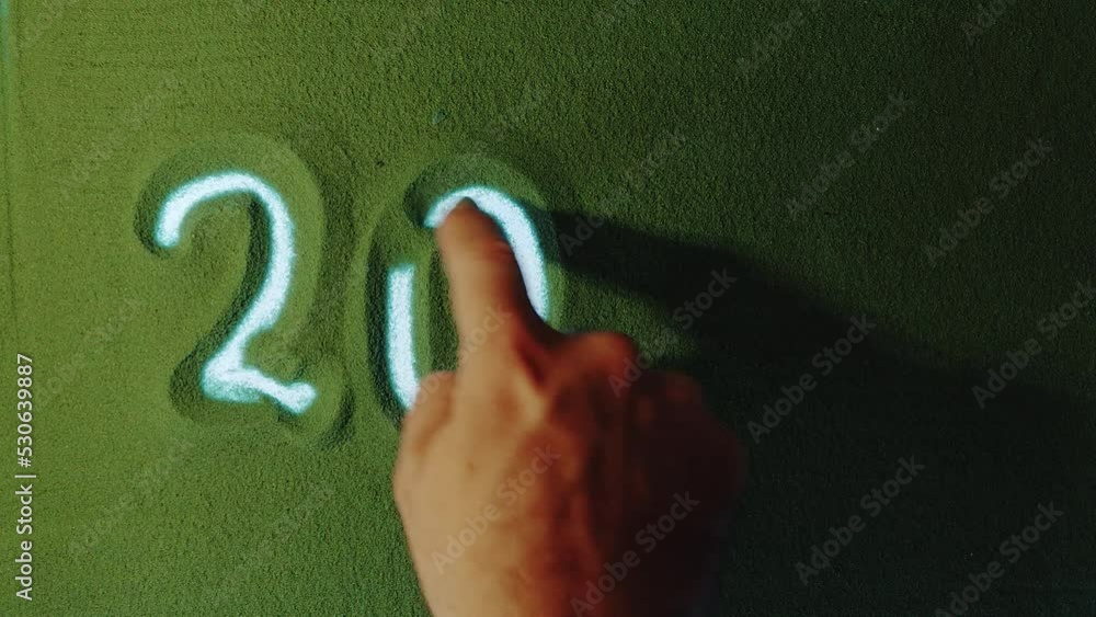 Hand drawing Year Number 2014 Symbol in the Green Sand. Male hand ...