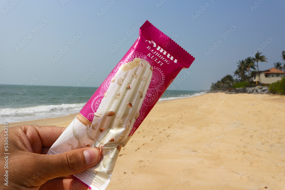 Close-up. A young man holds in his hand an ice cream Rajbhog kulfi ...