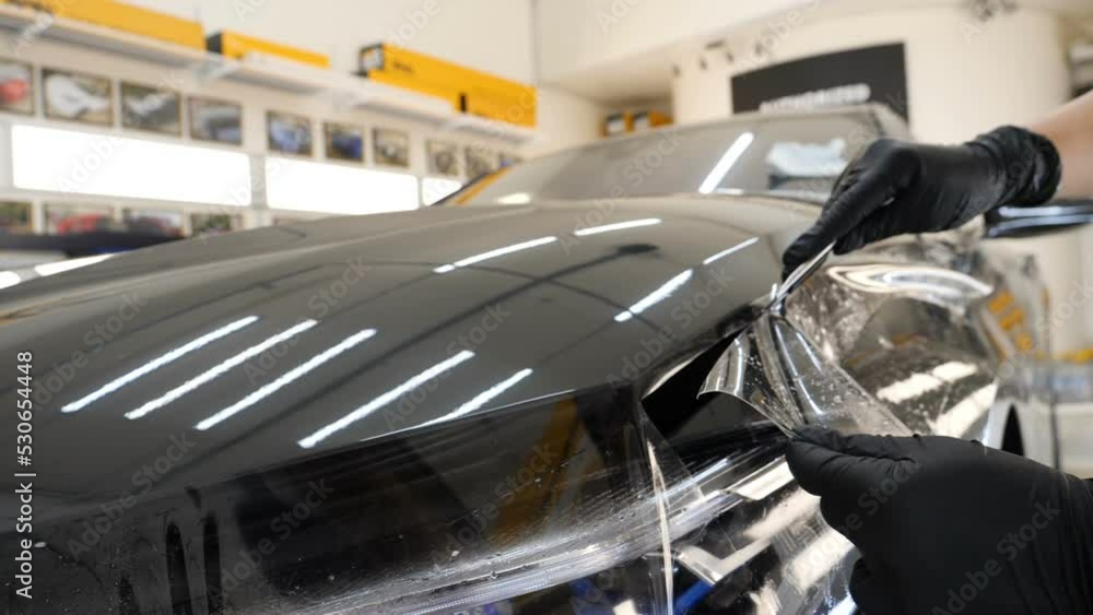 Close up to PPF installation process on a front headlight and hood. PPF ...
