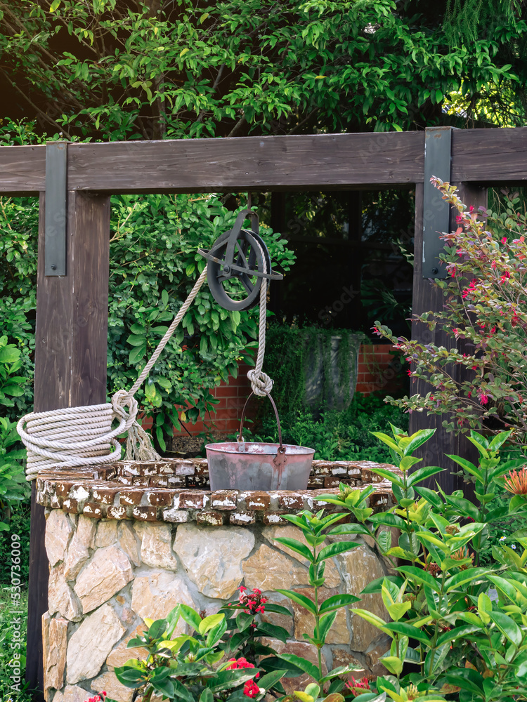 Beautiful artesian well made by stones and wheel pulley with metal ...