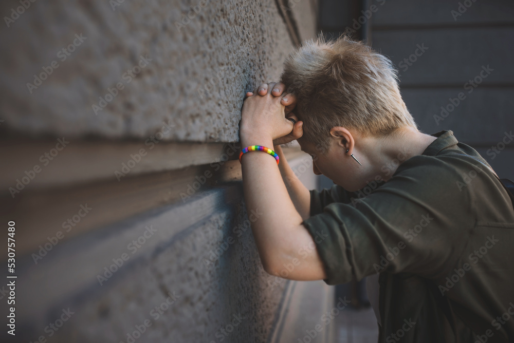 A young blonde woman with a short haircut shows a close-up of a rainbow ...
