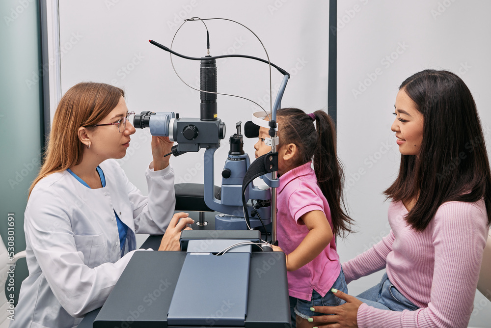 Japanese mother with her daughter while visit to optometrist. Little ...