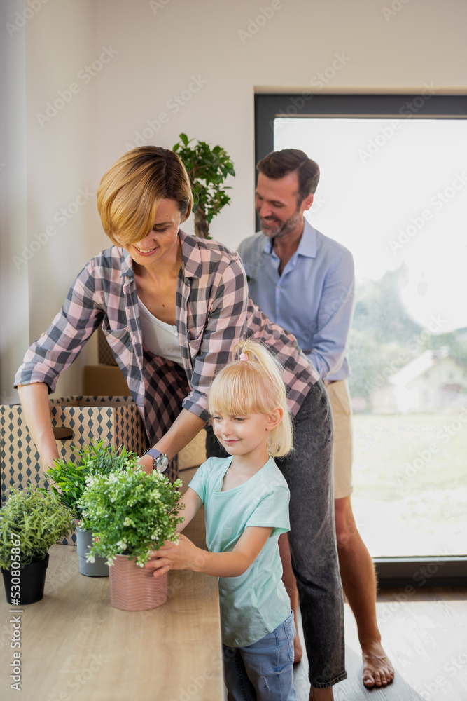 Happy family moving to their new house opening cardboard boxes together ...