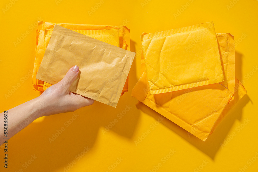 Foto de Hand with yellow paper envelope, postal parcel. Kraft bag ...
