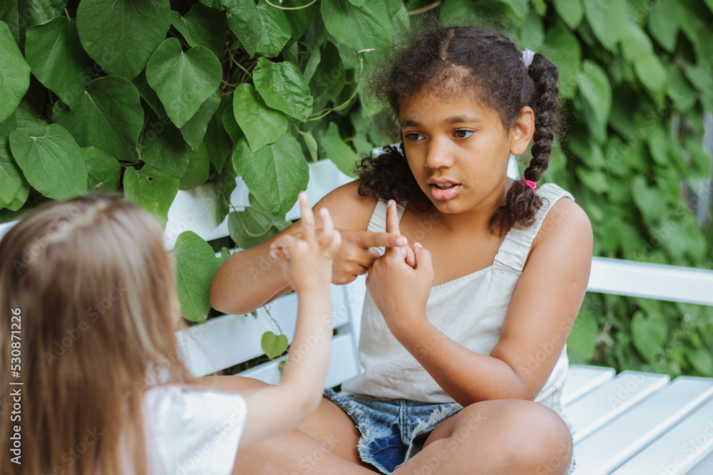children communicate in sign language sitting on a bench on the street ...