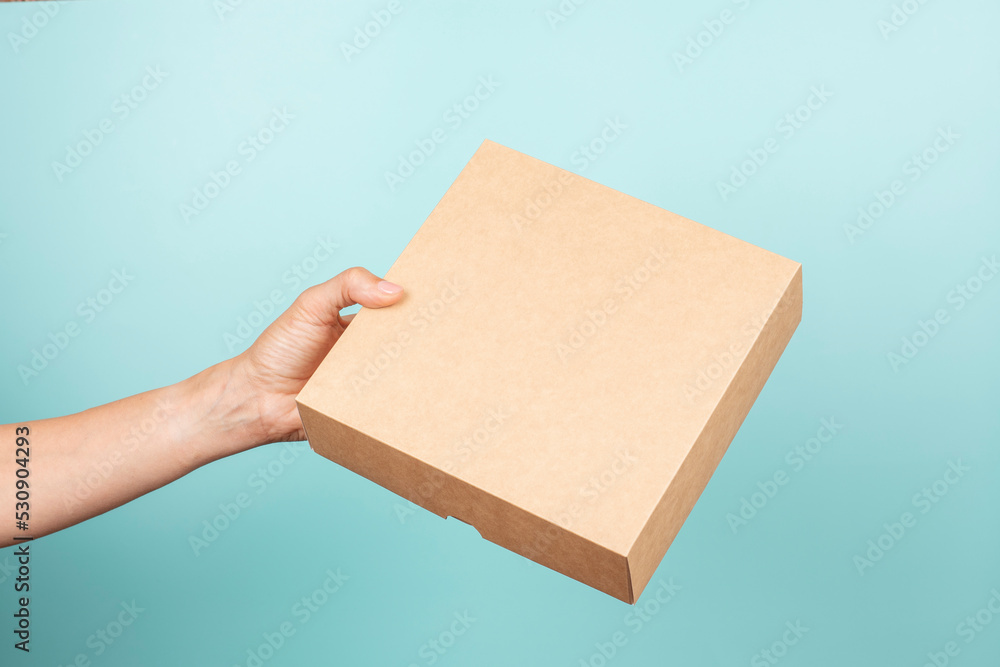 Foto de Mockup. Female hand holding brown rectangular cardboard box on ...