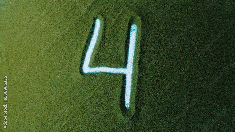 Hand drawing Number Four 4 Symbol in the Green Sand. Male hand writes a ...