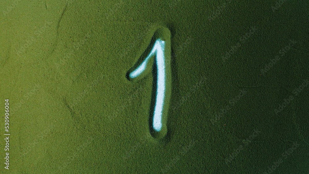 Hand drawing Number One 1 Symbol in the Green Sand. Male hand writes a ...