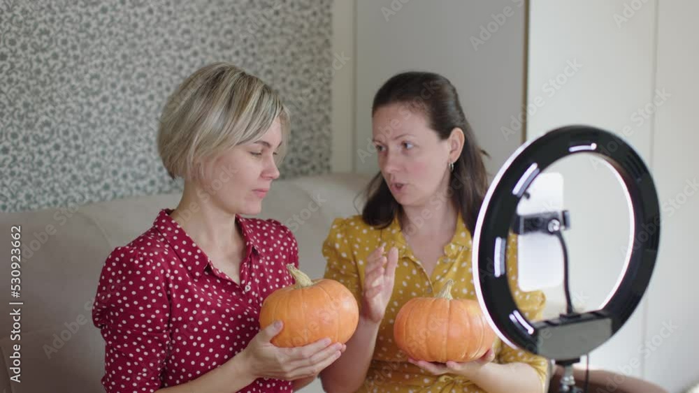 two female bloggers shoot video for blog hold pumpkins in hands talk ...