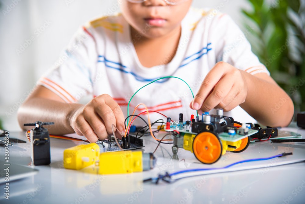 Asian kid boy plugging energy and signal cable to sensor chip with ...