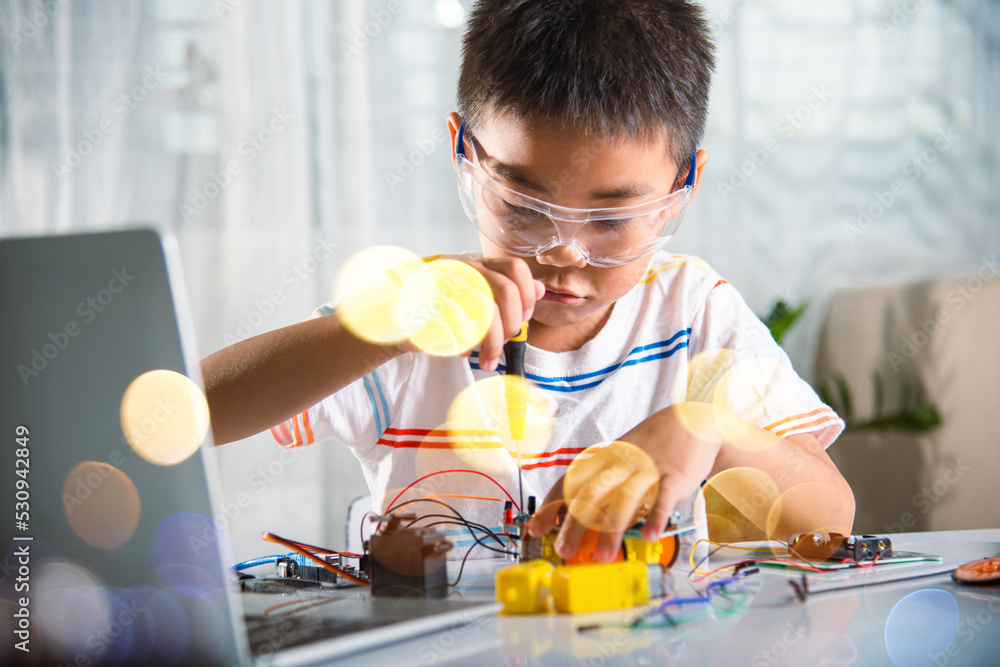 Little child tighten the nut with a screwdriver to assemble car toy, Asian kid boy assembling ...