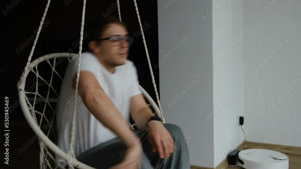 Young man in white shirt sit in White wicker swing chair and smile ...