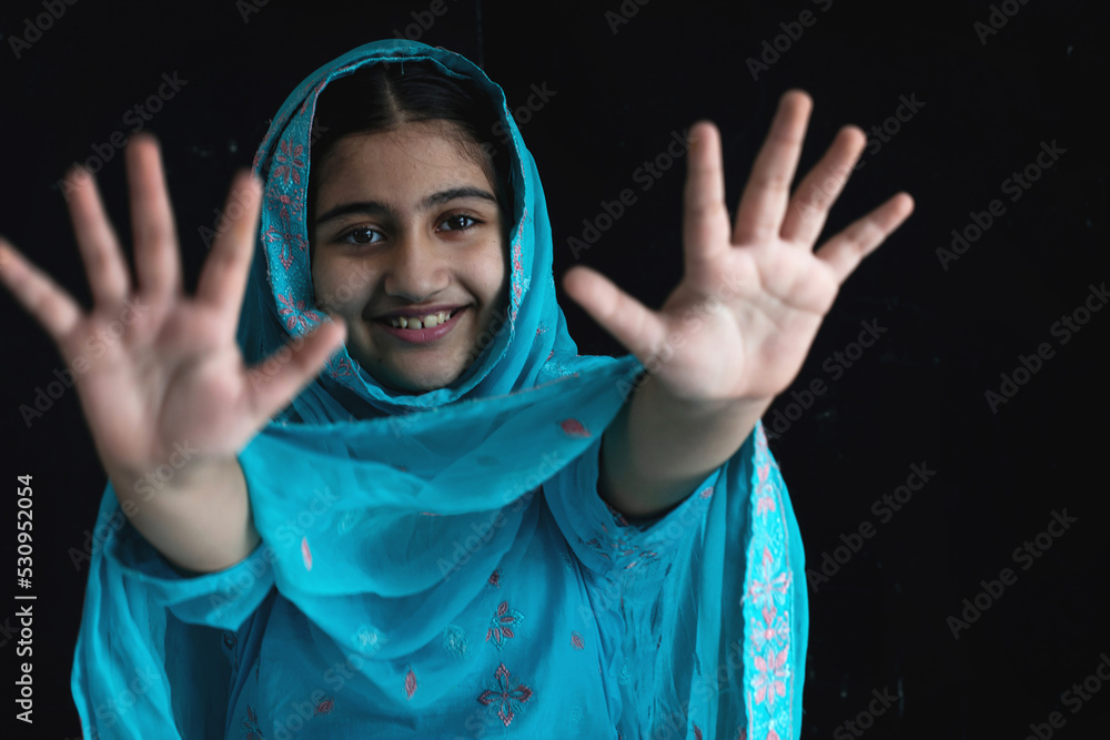 Little Muslim girl with beautiful eyes wearing blue hijab waving hands ...