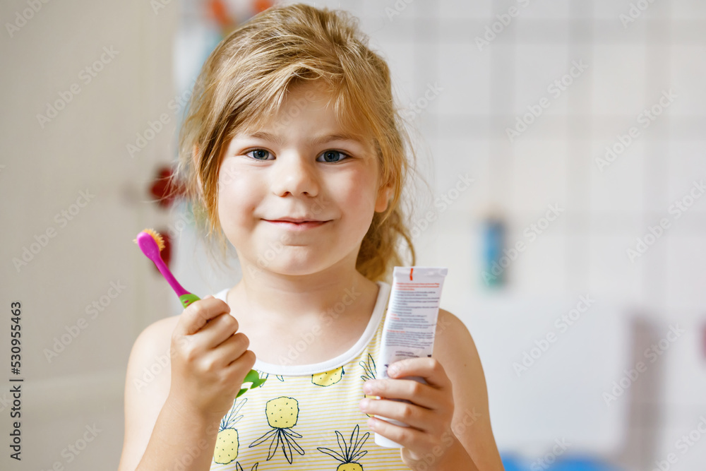 Cute little girl with a toothbrush and toothpaste in her hands cleans ...