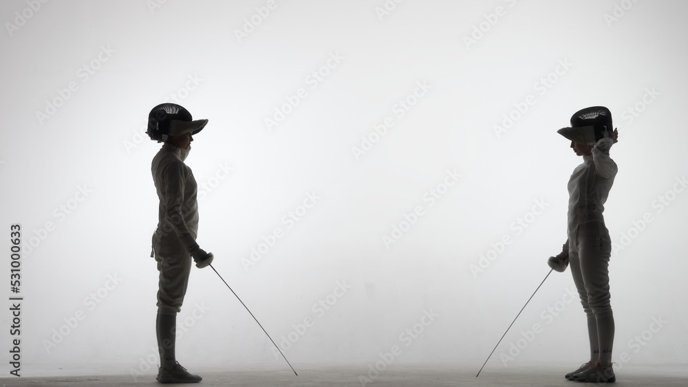 Side view of two young female swordswoman with rapiers. Athletes in ...