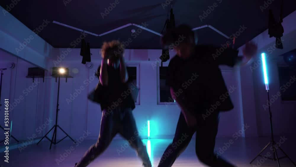 Two professional twin dancers dancing modern dance in the dance hall in ...