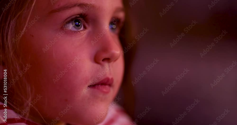 Little girl watching the color screen of the projector in the cinema ...