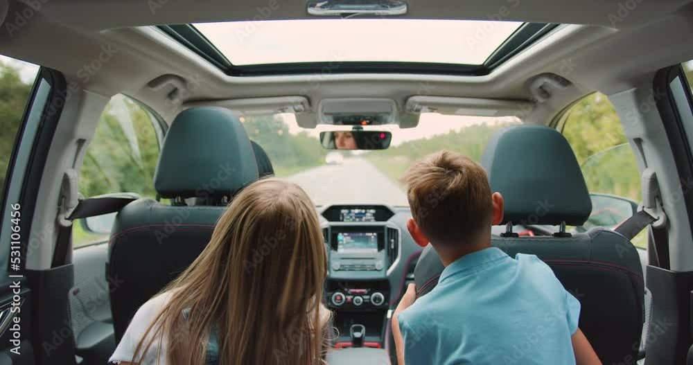 Rear view. Children boy and girl sitting in back seat of car during ...