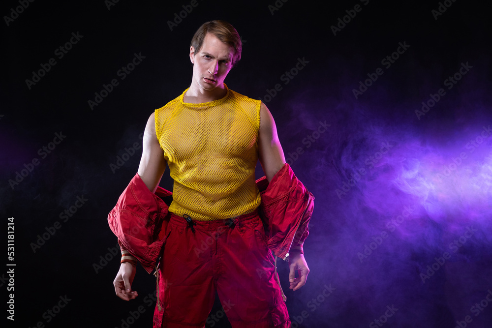 a young muscular man in a bright outfit poses in a pretentious pose ...
