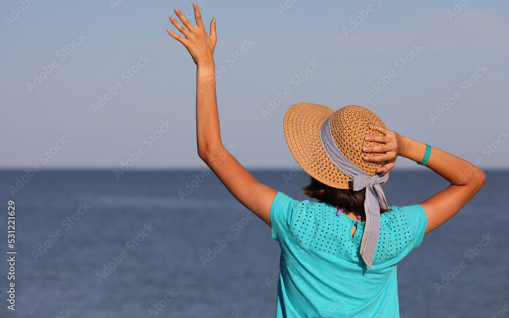 young girl with boater straw hat by the sea during summer vacation ...