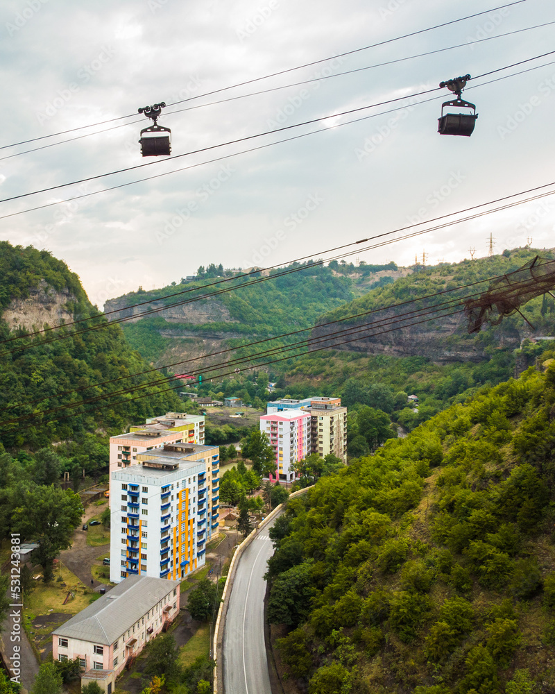 Aerial rising view ropeway with metal buckets with load above road in ...