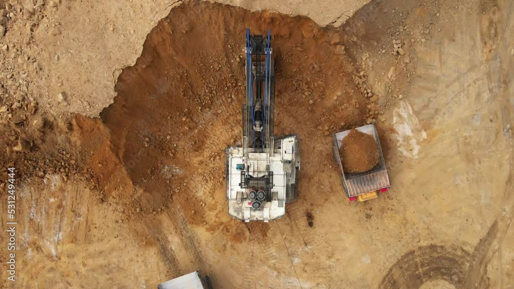 top view of an excavator loading ground onto the big dump truck ...