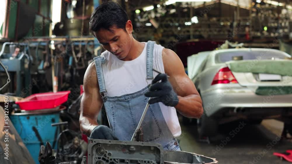Asian male car engineer fixing engine power transmission gears box at ...