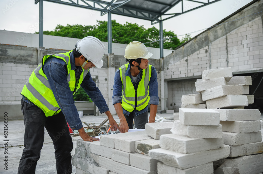 Civil engineers discuss with foreman or builder while opening ...