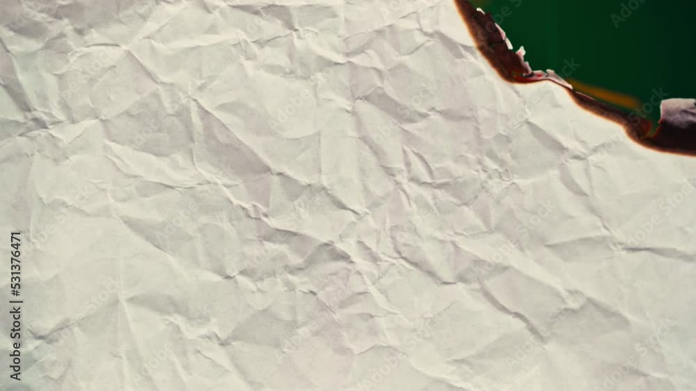 White paper burns from above on a green background copy space. The ...