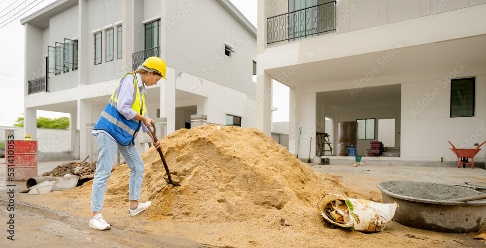 Female construction worker with a vest and hardhat standing on dirty ...