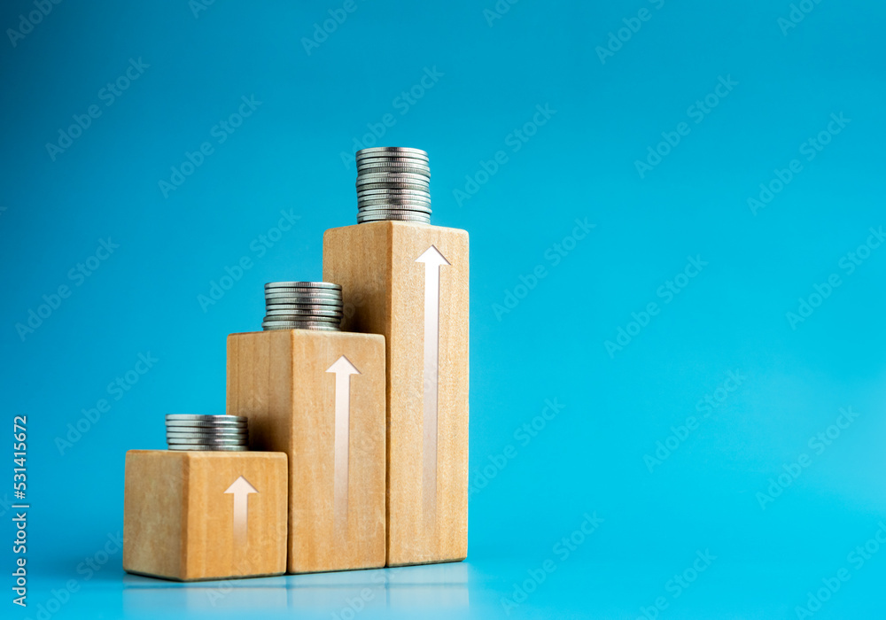 Shining rise up arrow on wooden cube blocks top with coins stacked, bar ...