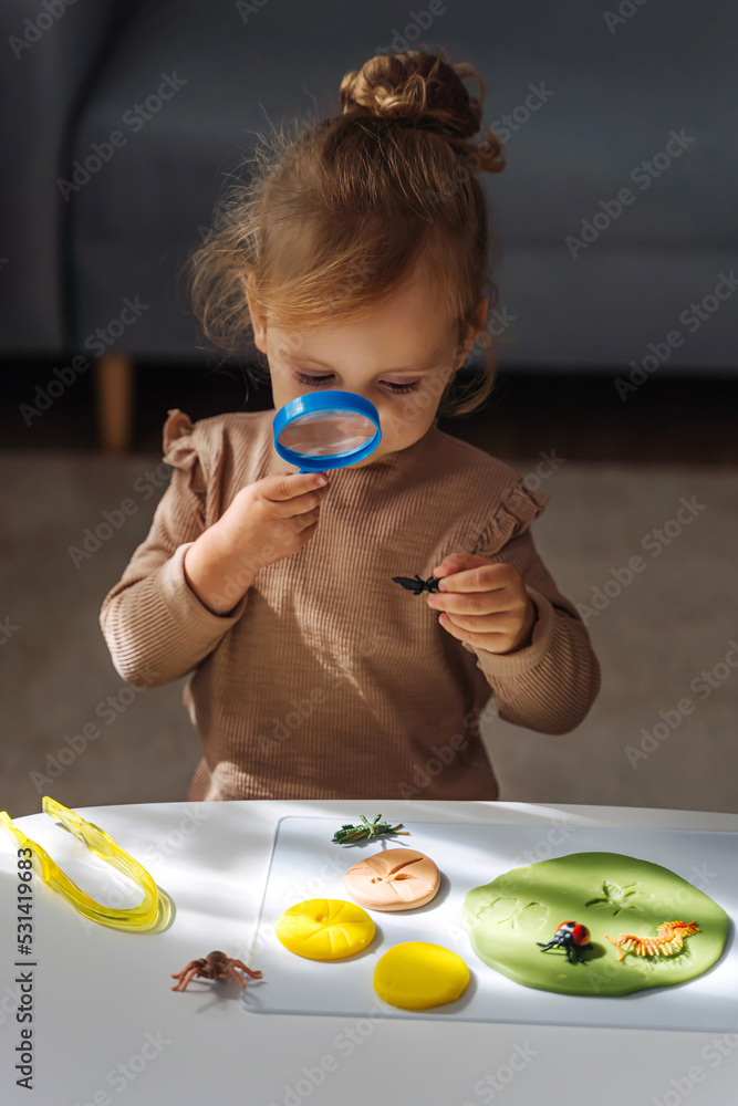 A little girl playing with toy insects. Educational game Bug Fossils ...